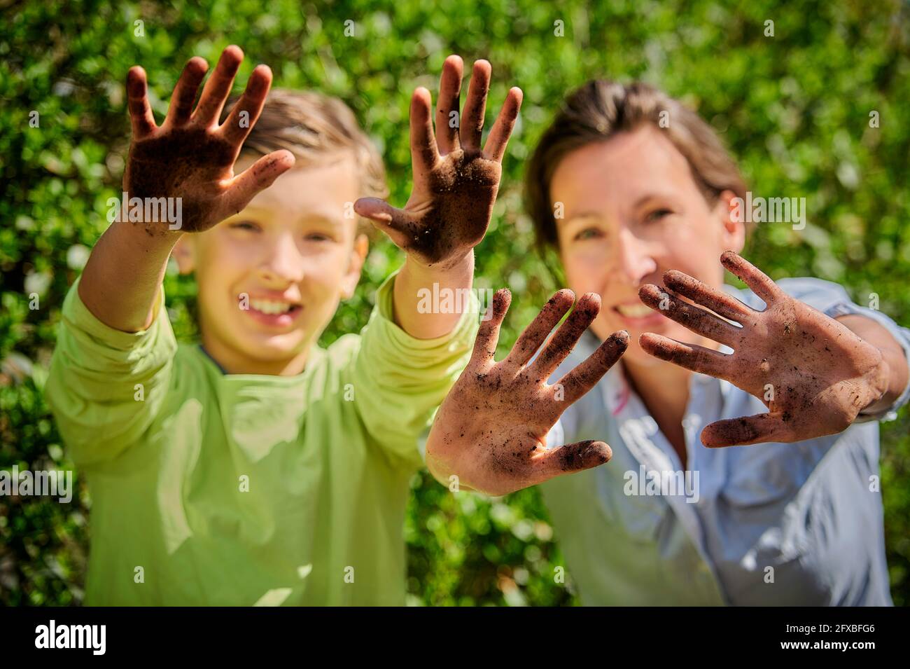 Mother with son showing mud hands in garden during sunny day Stock ...