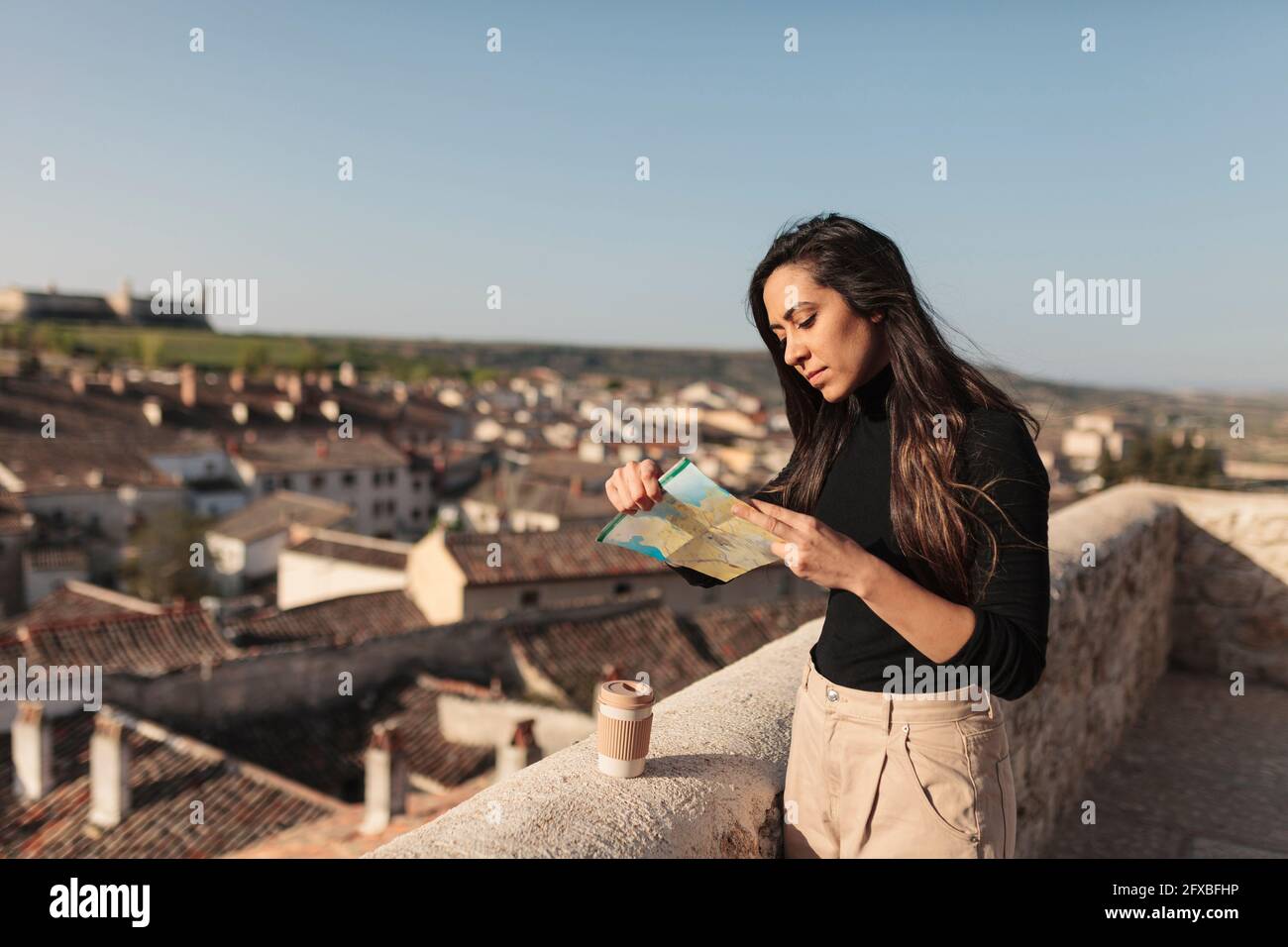 Female tourist checking map while standing by retaining wall Stock ...