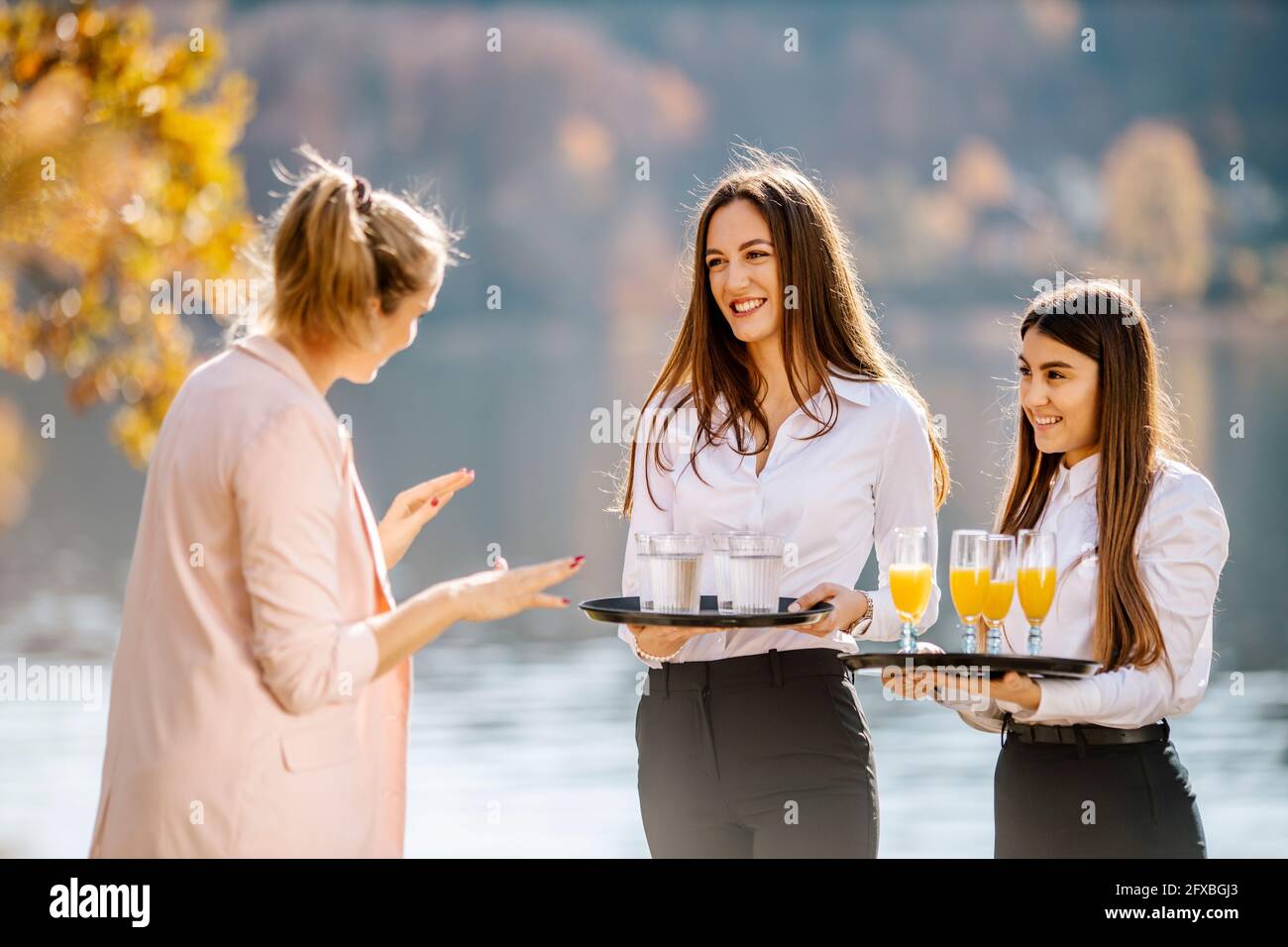 Female event planner instructing waitress holding drink trays Stock ...