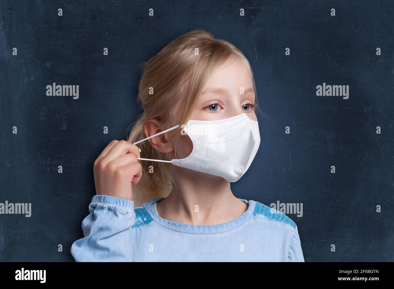 Girl pulling string of face mask against black background Stock Photo ...
