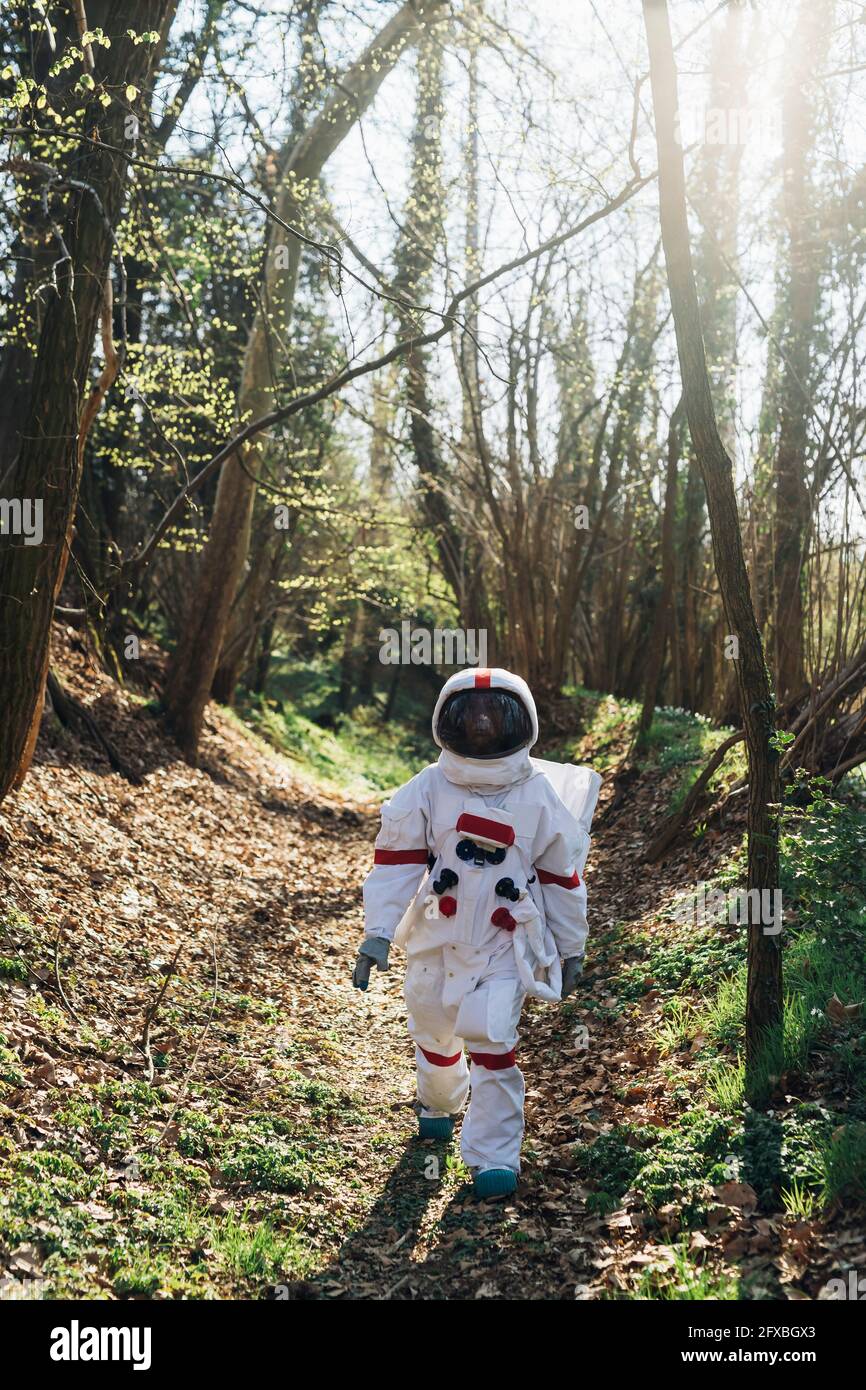 Female explorer in space suit and helmet walking on footpath Stock ...