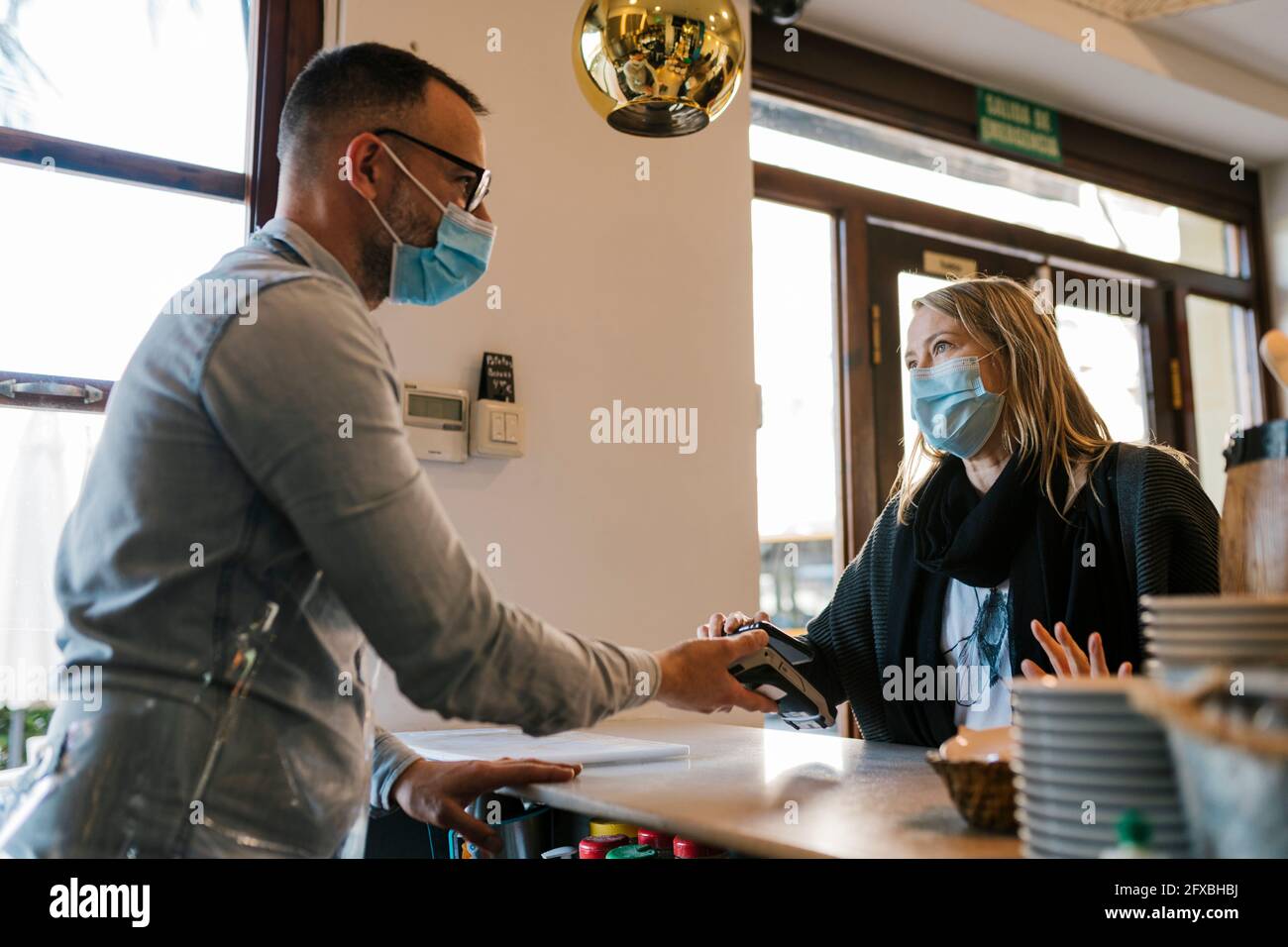 Waiter and female customer discussing while doing contactless payment ...
