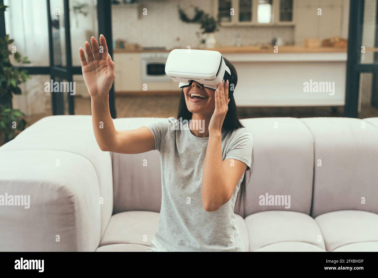Smiling woman gesturing wearing Virtual reality headset while sitting ...
