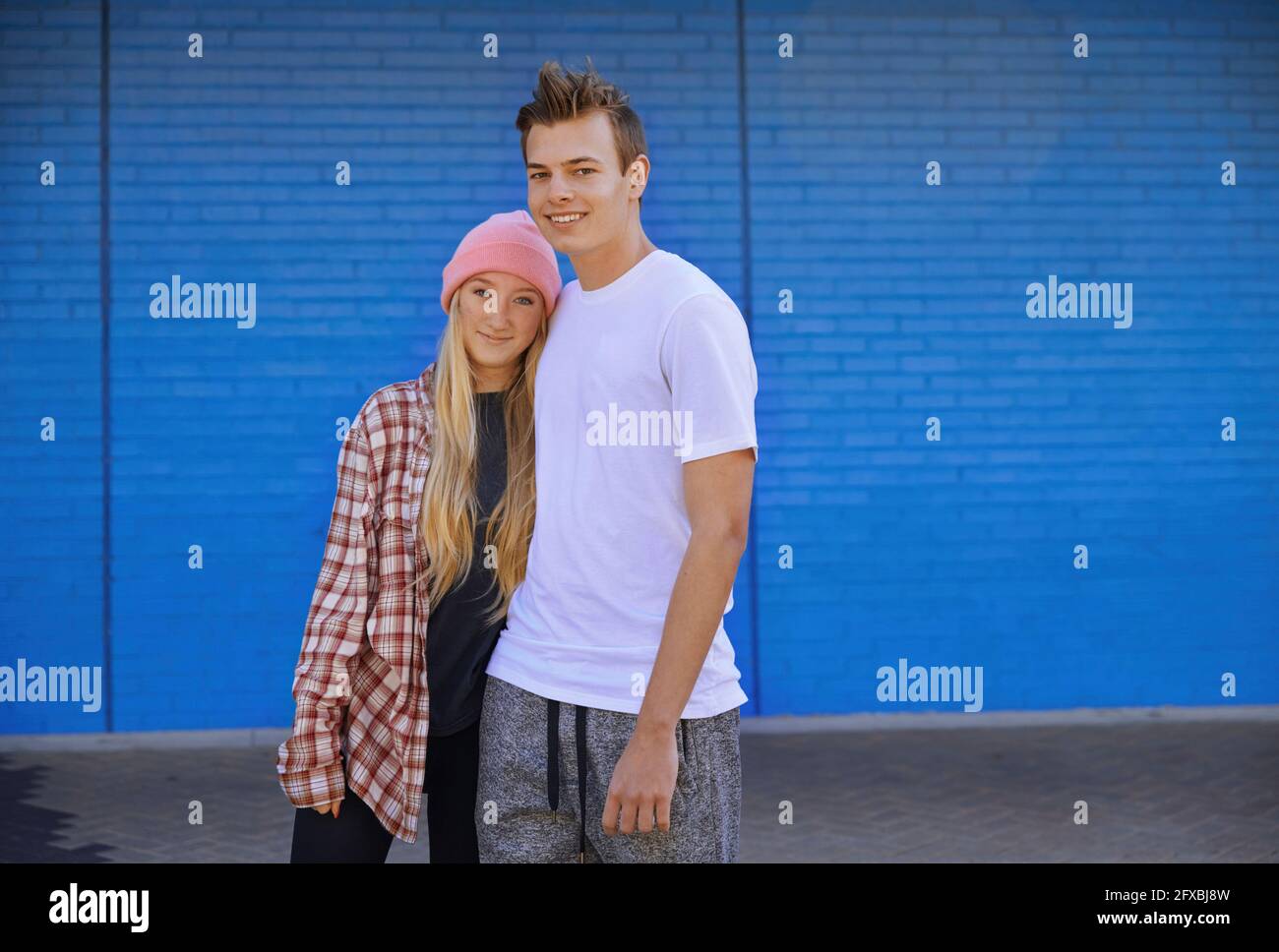 Girlfriend standing with boyfriend in front of blue wall Stock Photo ...