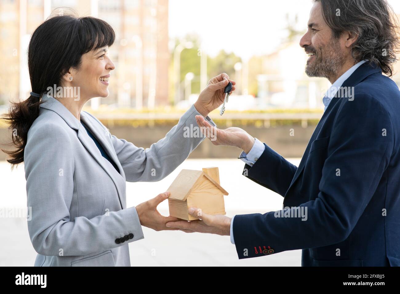 Mature professional smiling while taking house key and model through ...