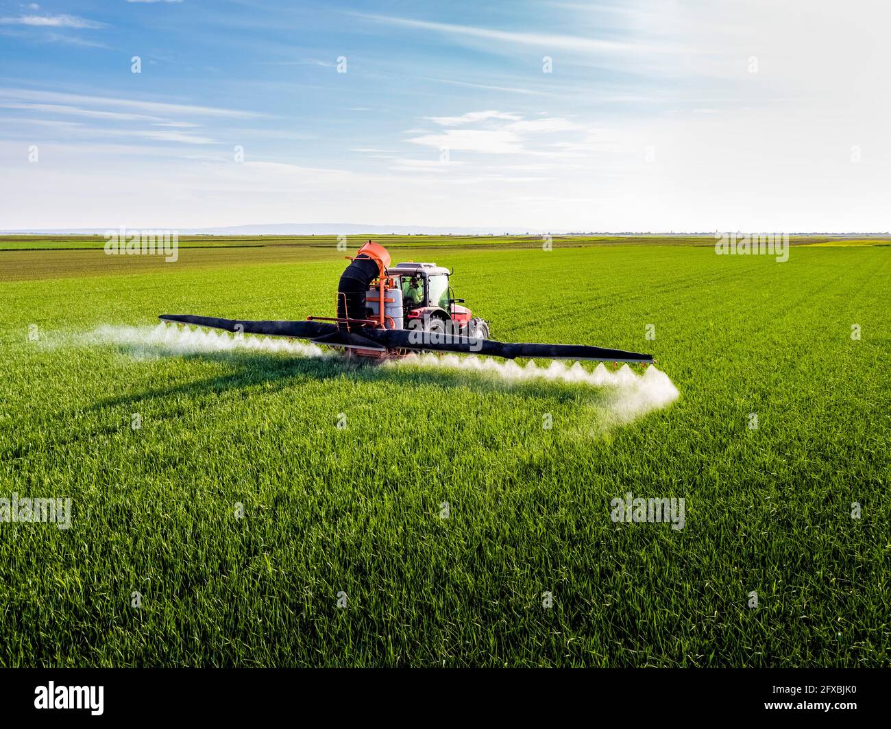 Farmer fertilizing crop through crop sprayer in field Stock Photo - Alamy