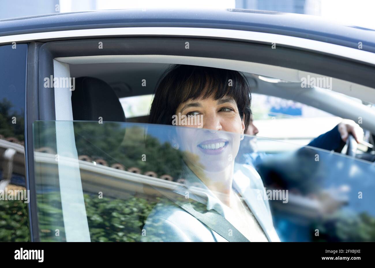 Mature businesswoman smiling while looking through car window Stock ...