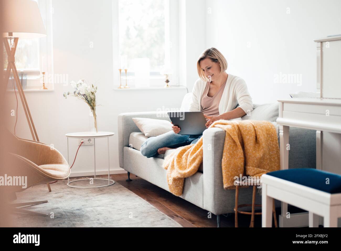 Female entrepreneur using laptop on sofa at home Stock Photo - Alamy