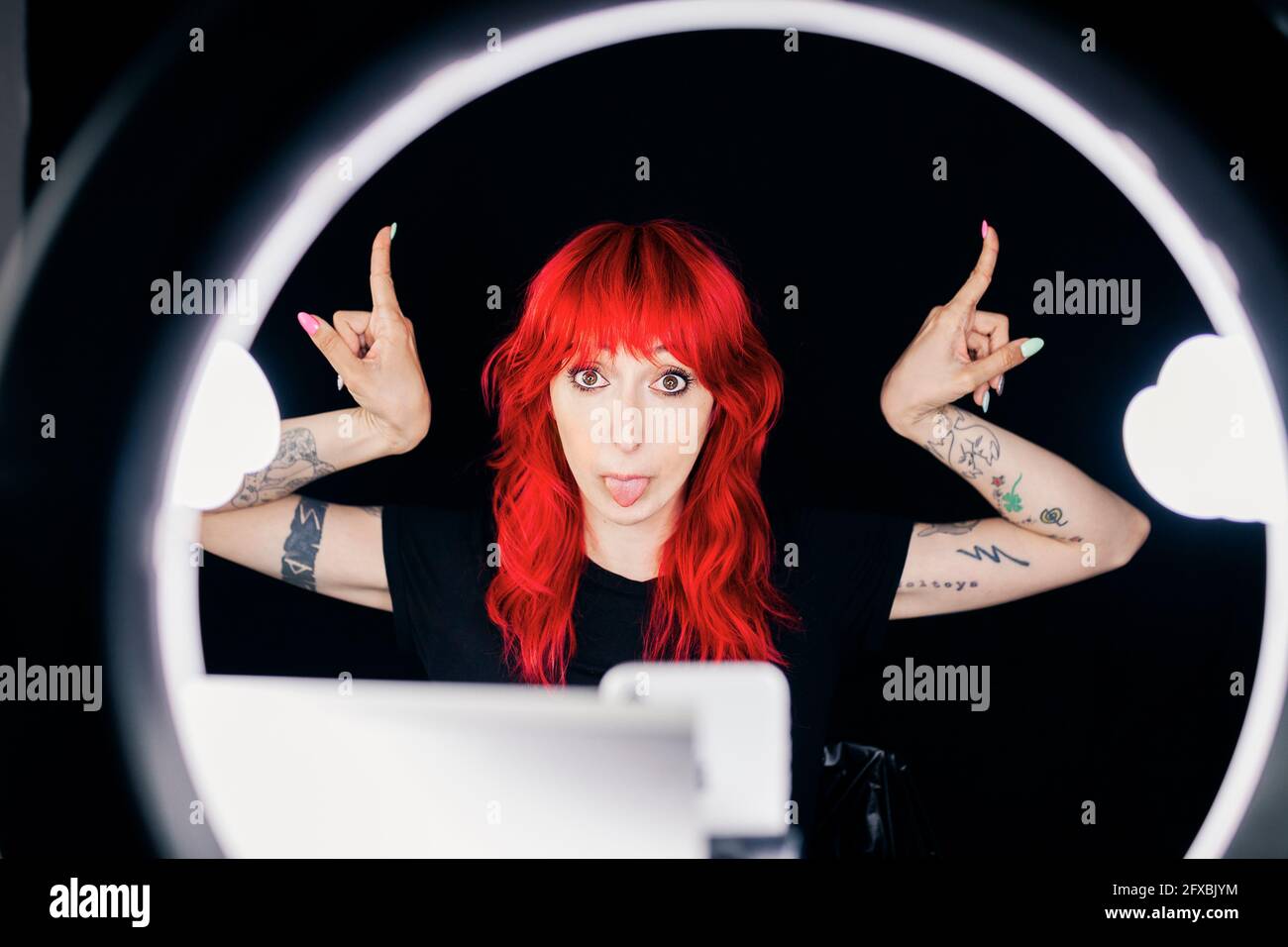 Female vlogger making face during vlogging through mobile phone in ...