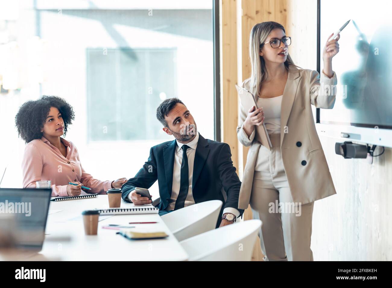 Female professional explaining to colleagues in meeting at office Stock ...