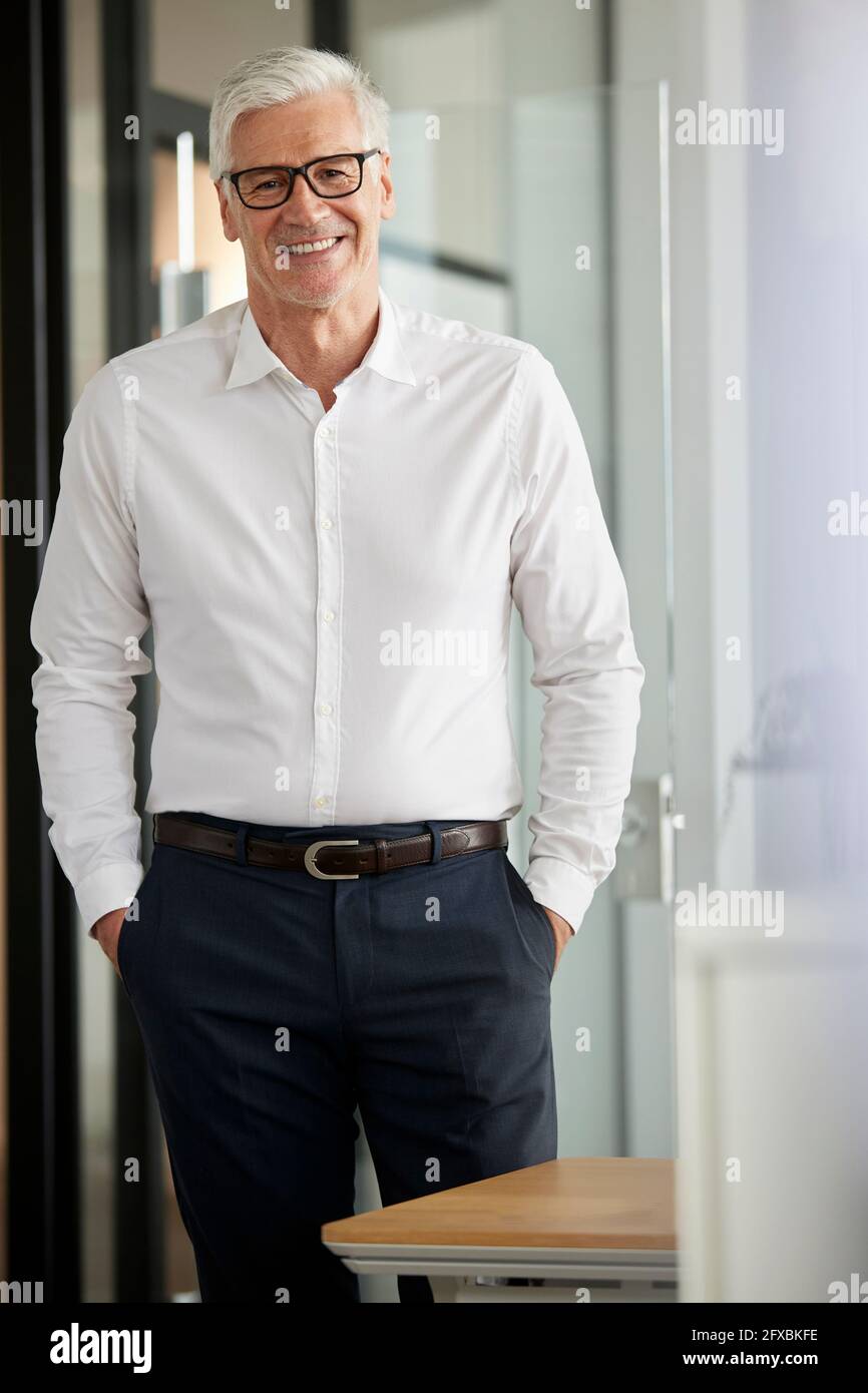 Smiling businessman standing with hands in pockets at office Stock ...