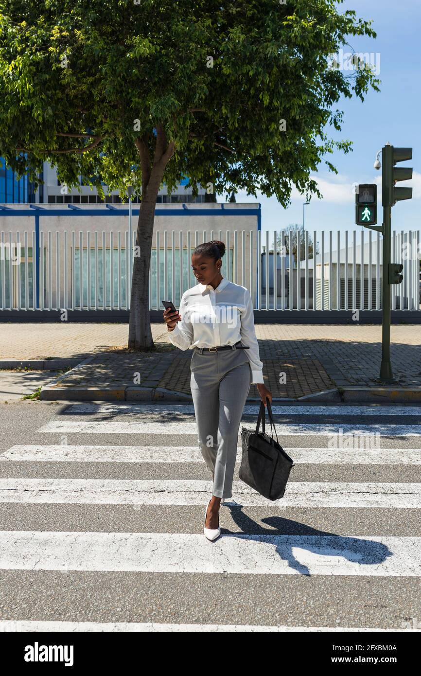 Female professional using mobile phone while walking on road Stock ...