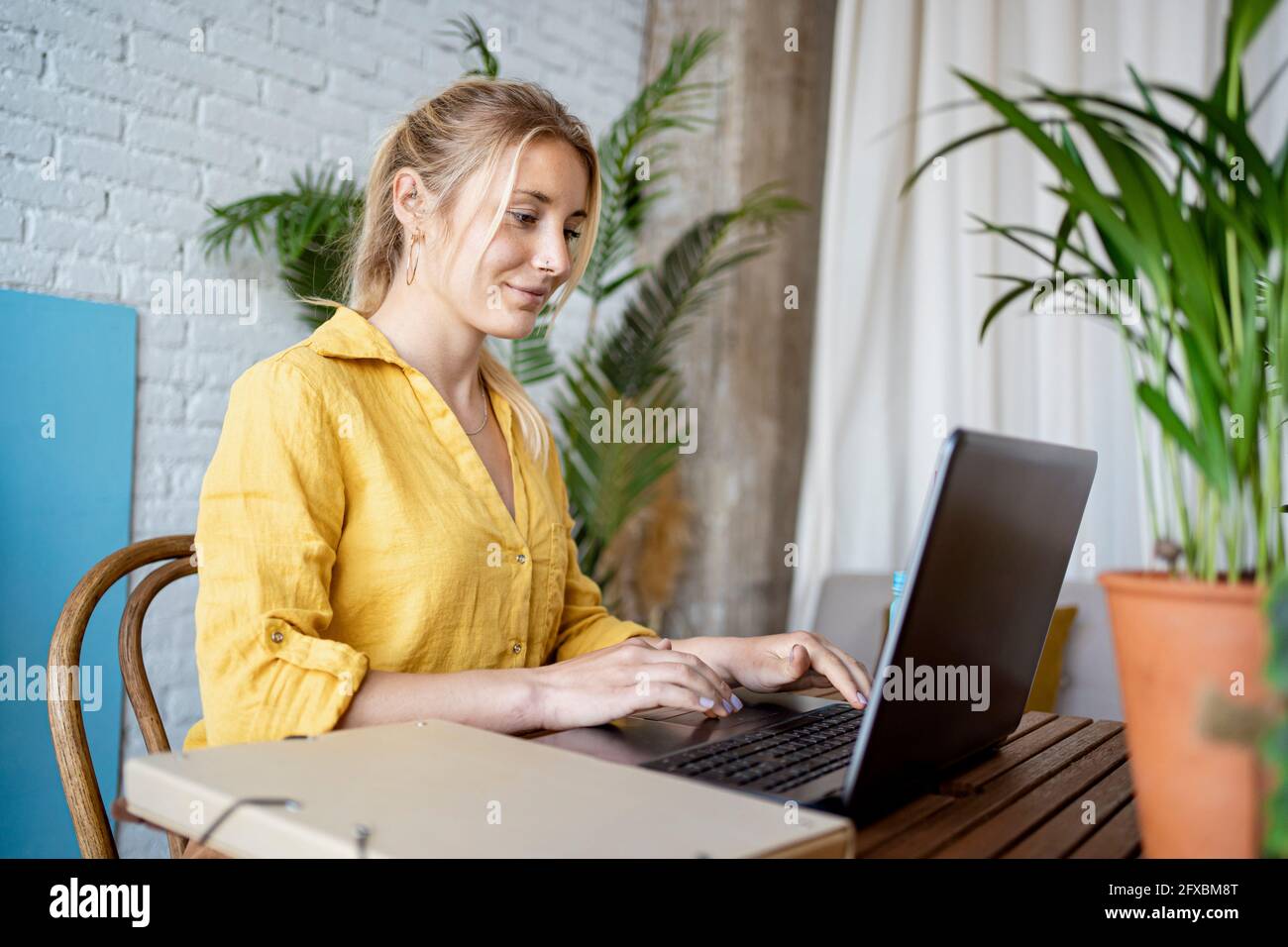 Female professional using laptop on desk while working at home office ...