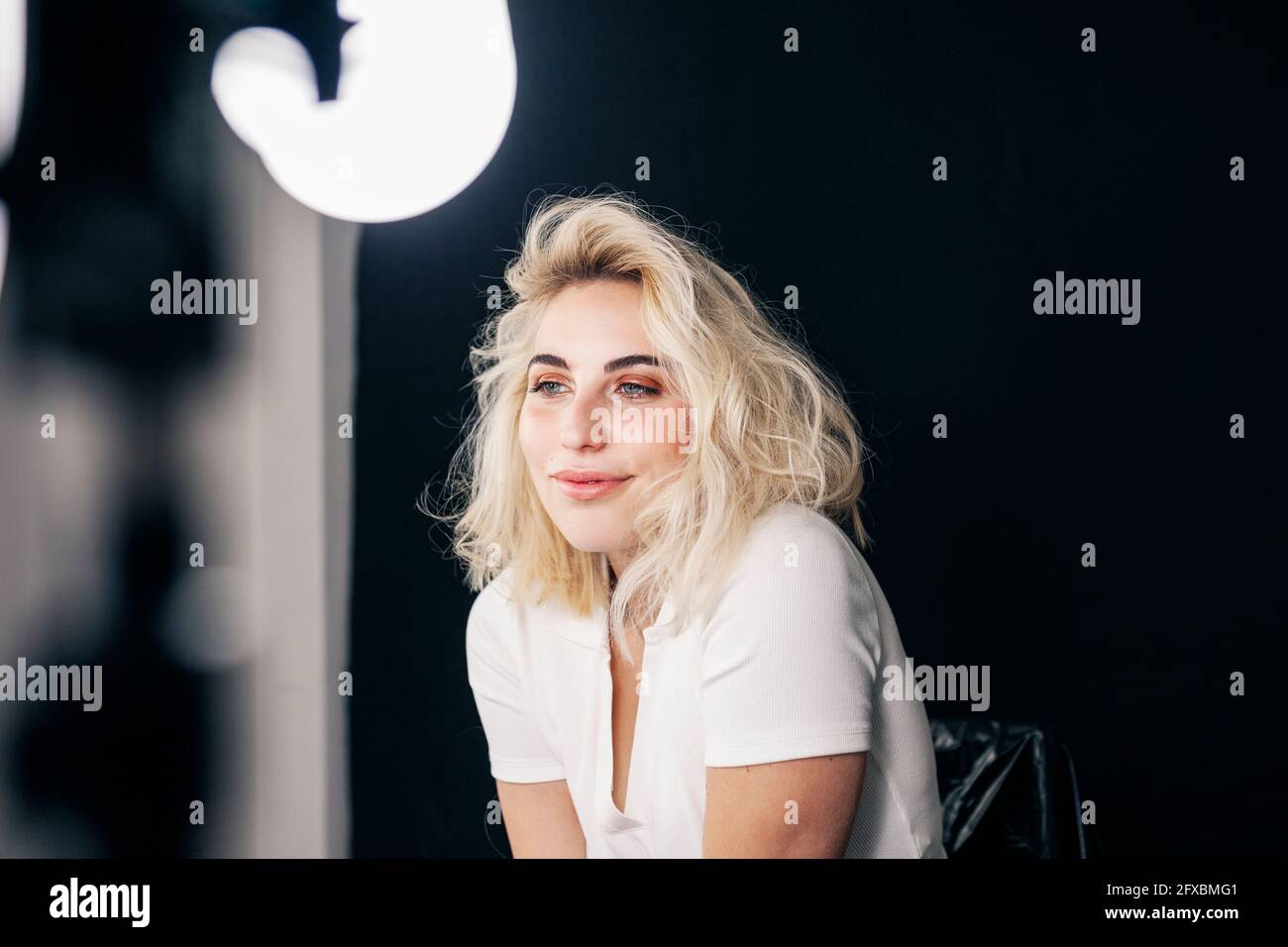 Beautiful young female model contemplating while sitting in studio ...