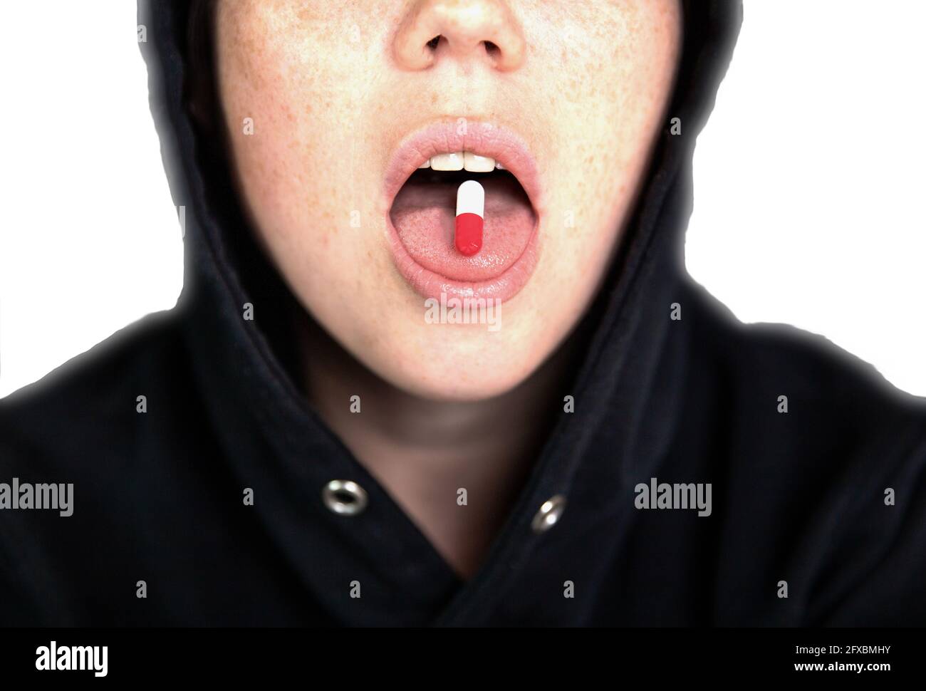 A woman is holding a pill, capsule with a drug on her tongue, teenager ...