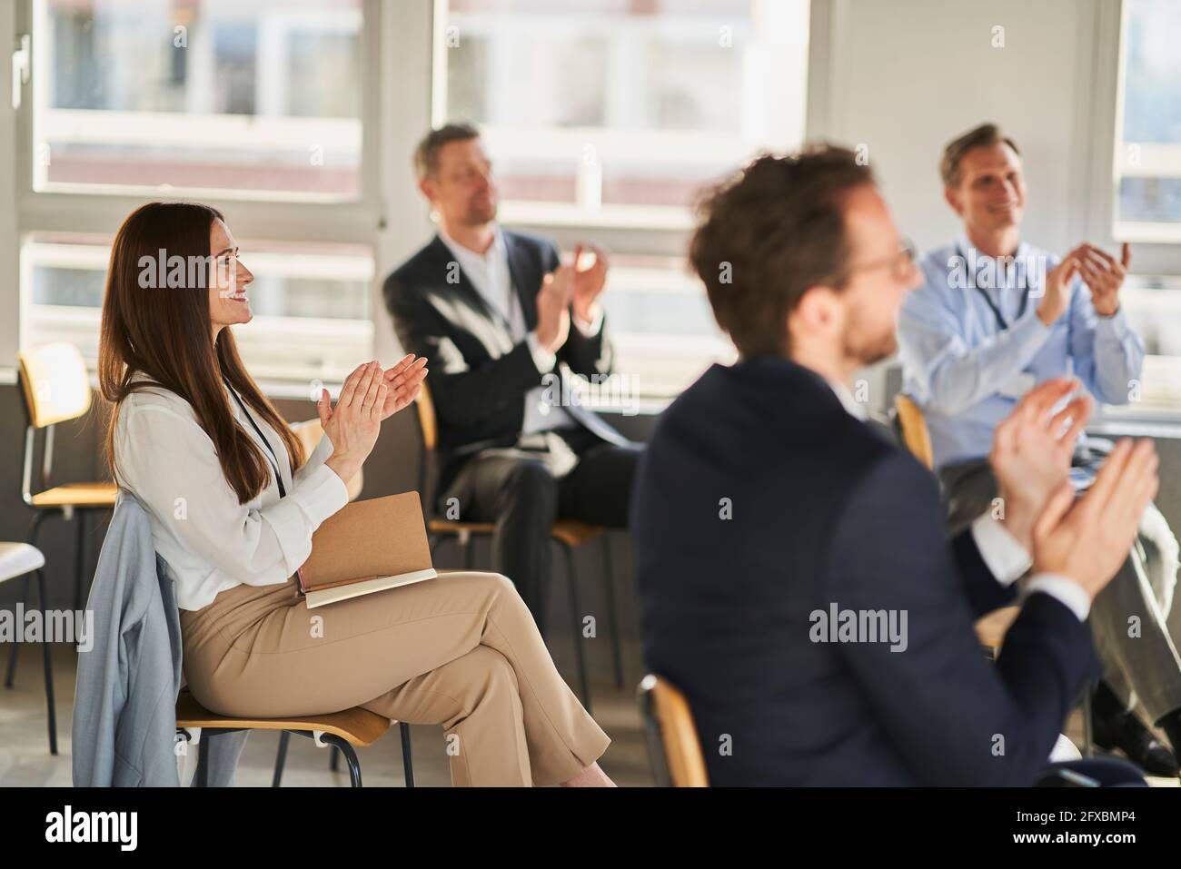 Businesswoman clapping hands with colleagues in education conference ...