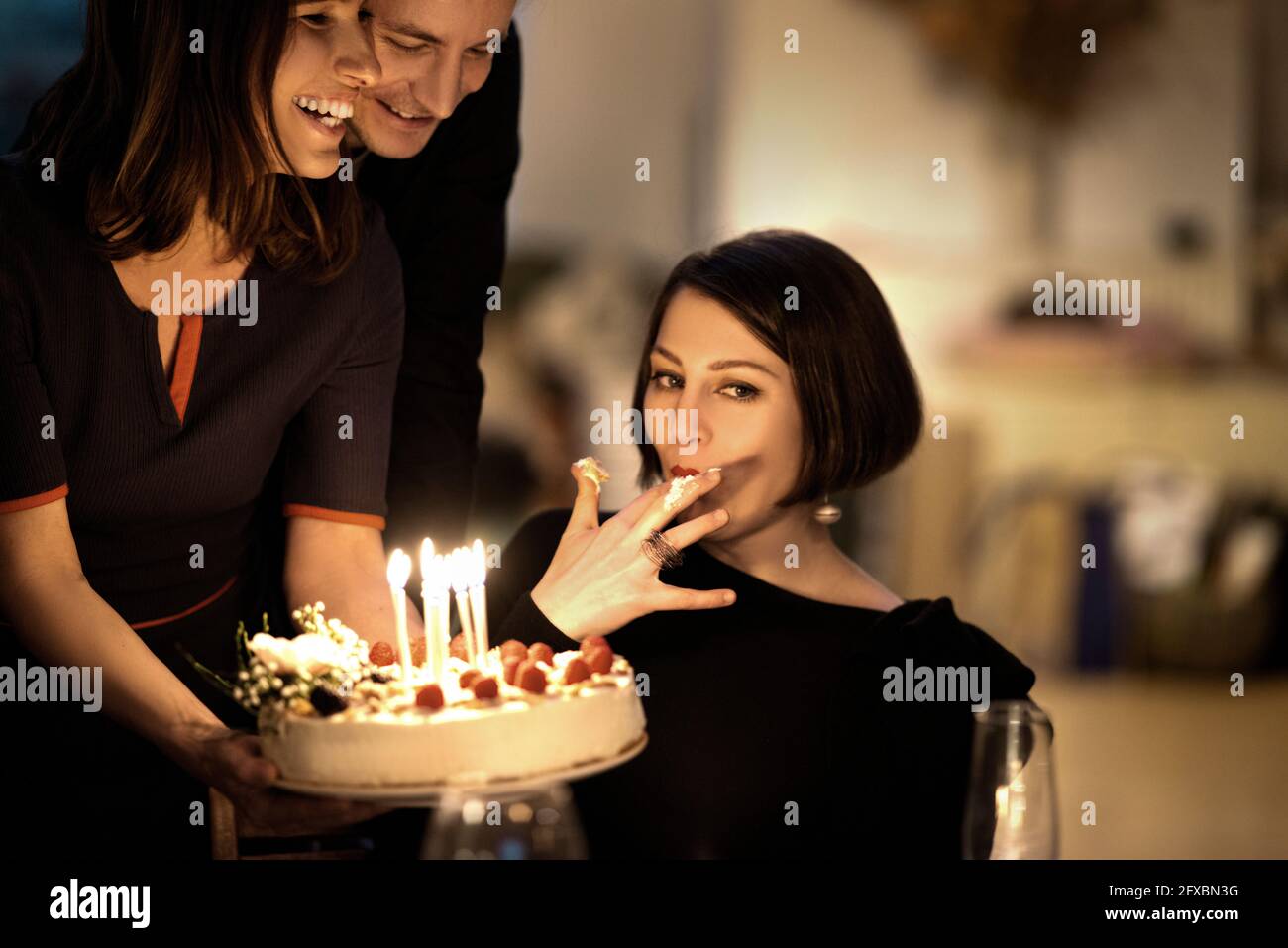 Beautiful woman eating cake by male and female friends during ...