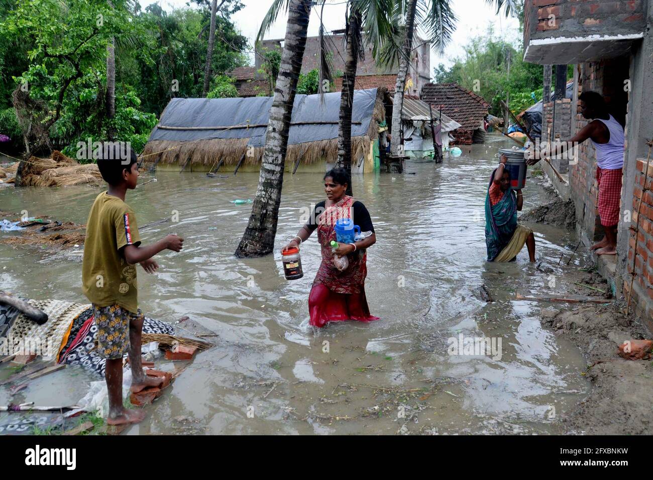 Namkhana, India. 26th May, 2021. Villagers wade through a flooded area ...