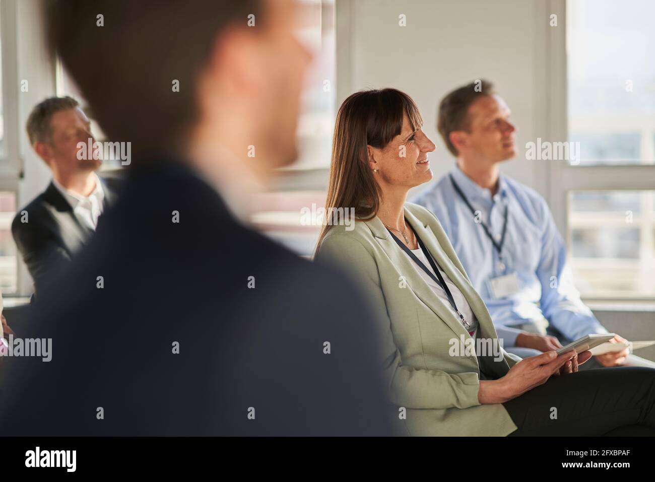 Mature businesswoman attending training class with colleagues at office ...