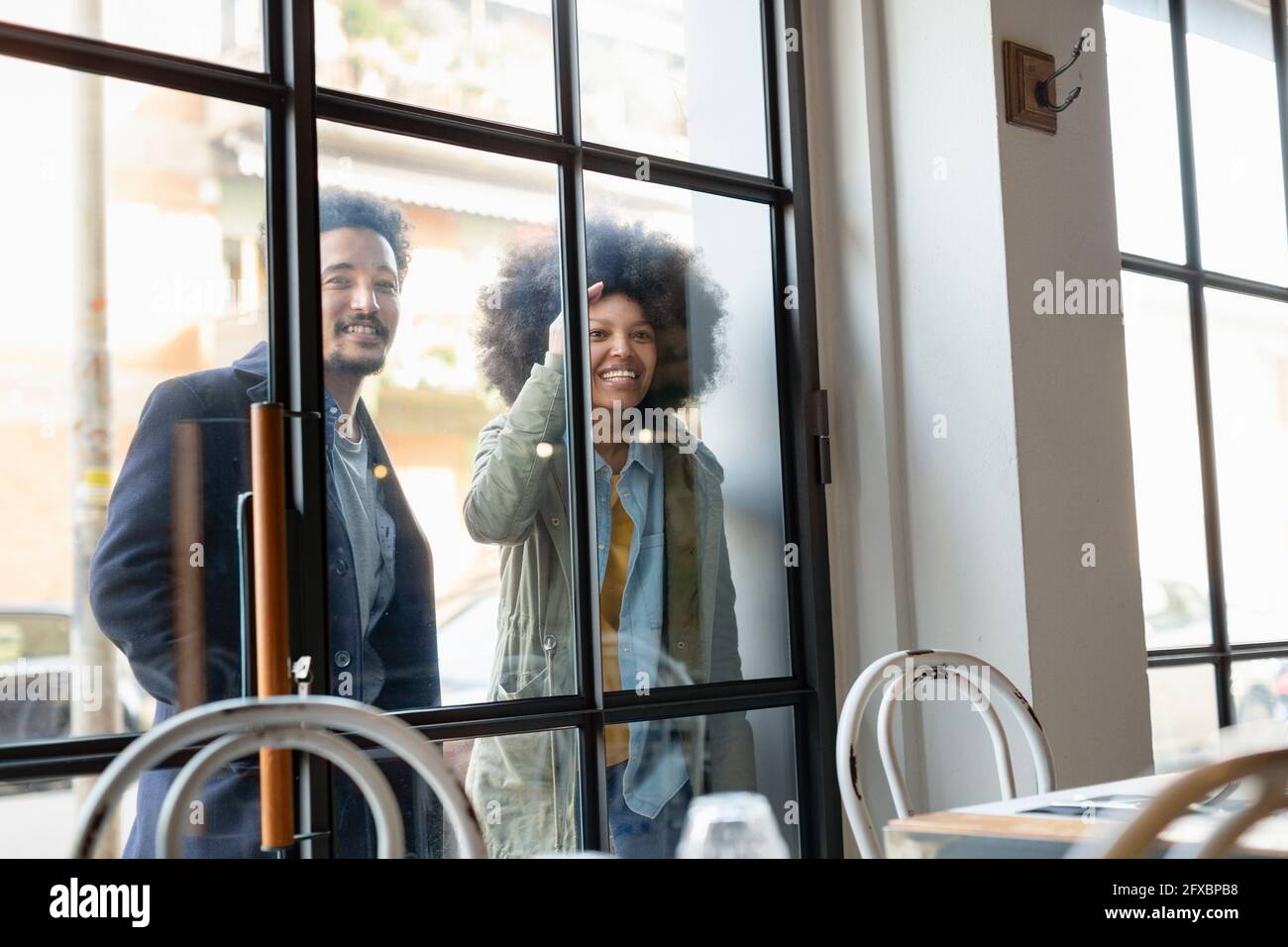 Couple looking inside cafe through glass window Stock Photo - Alamy