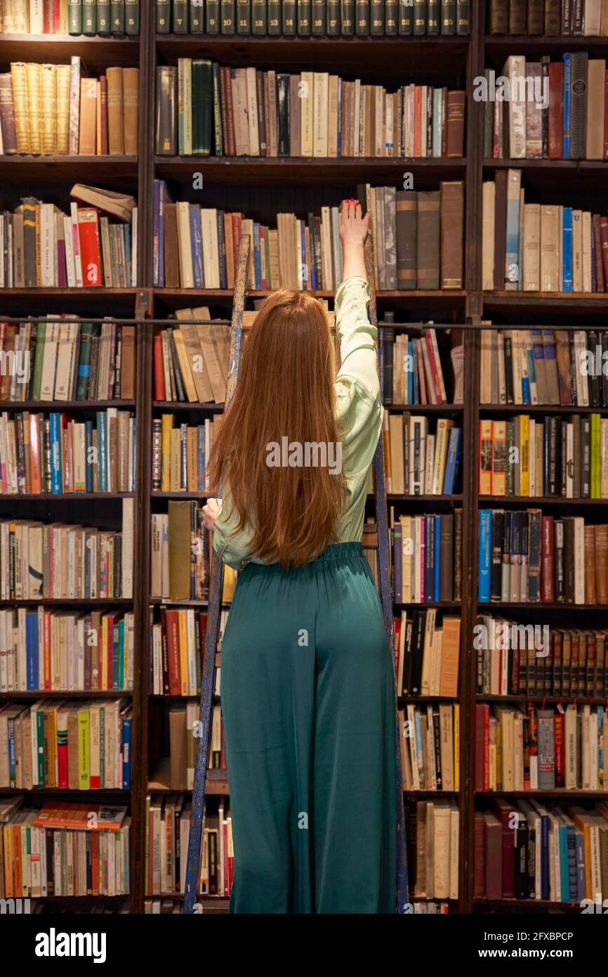 Young woman searching book in library Stock Photo - Alamy