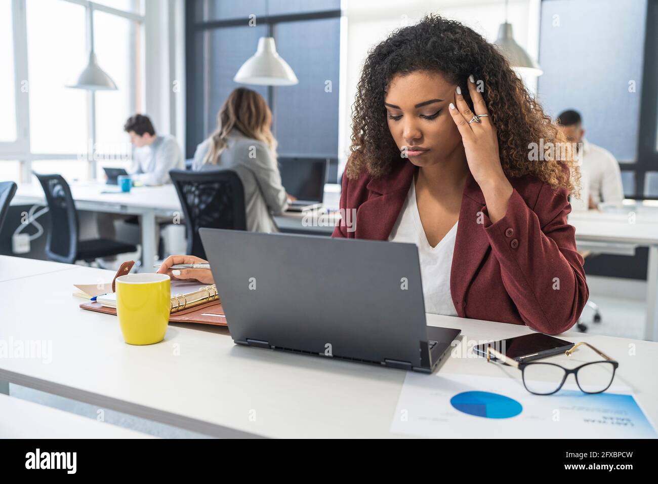 Confused female professional working with male and female colleagues in ...