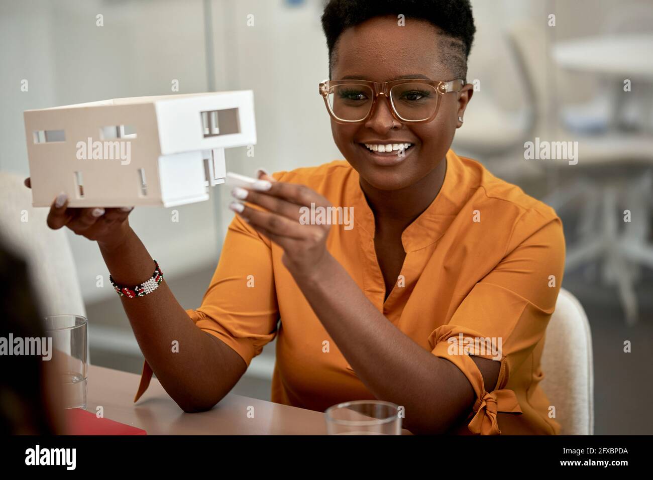 Smiling female architect holding architectural model at office Stock ...