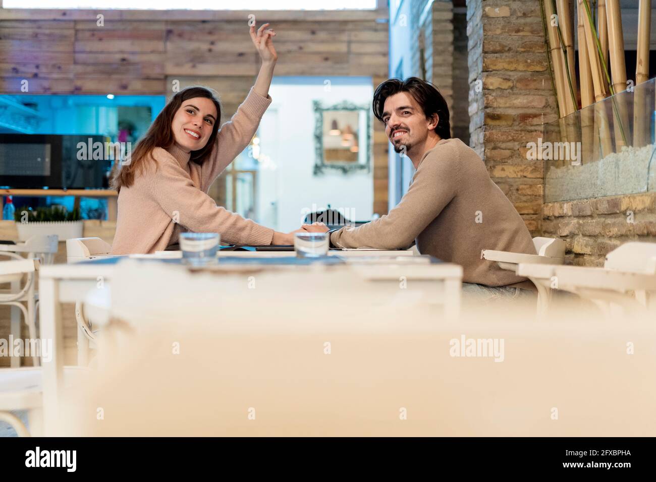 Young woman calling waiter while sitting with boyfriend at restaurant ...