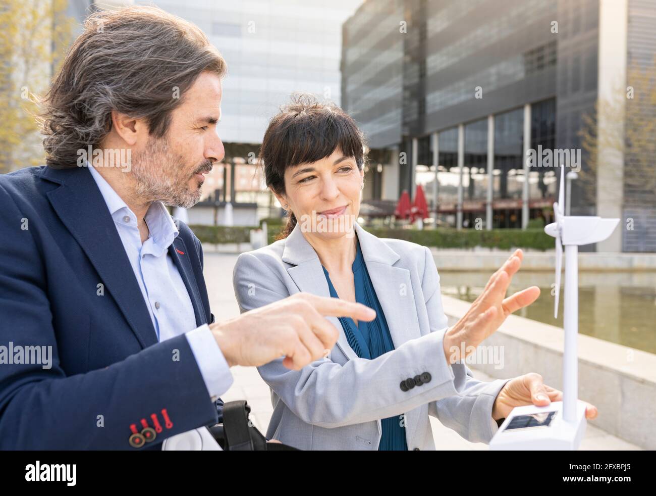 Mature female engineer explaining wind turbine model with male ...