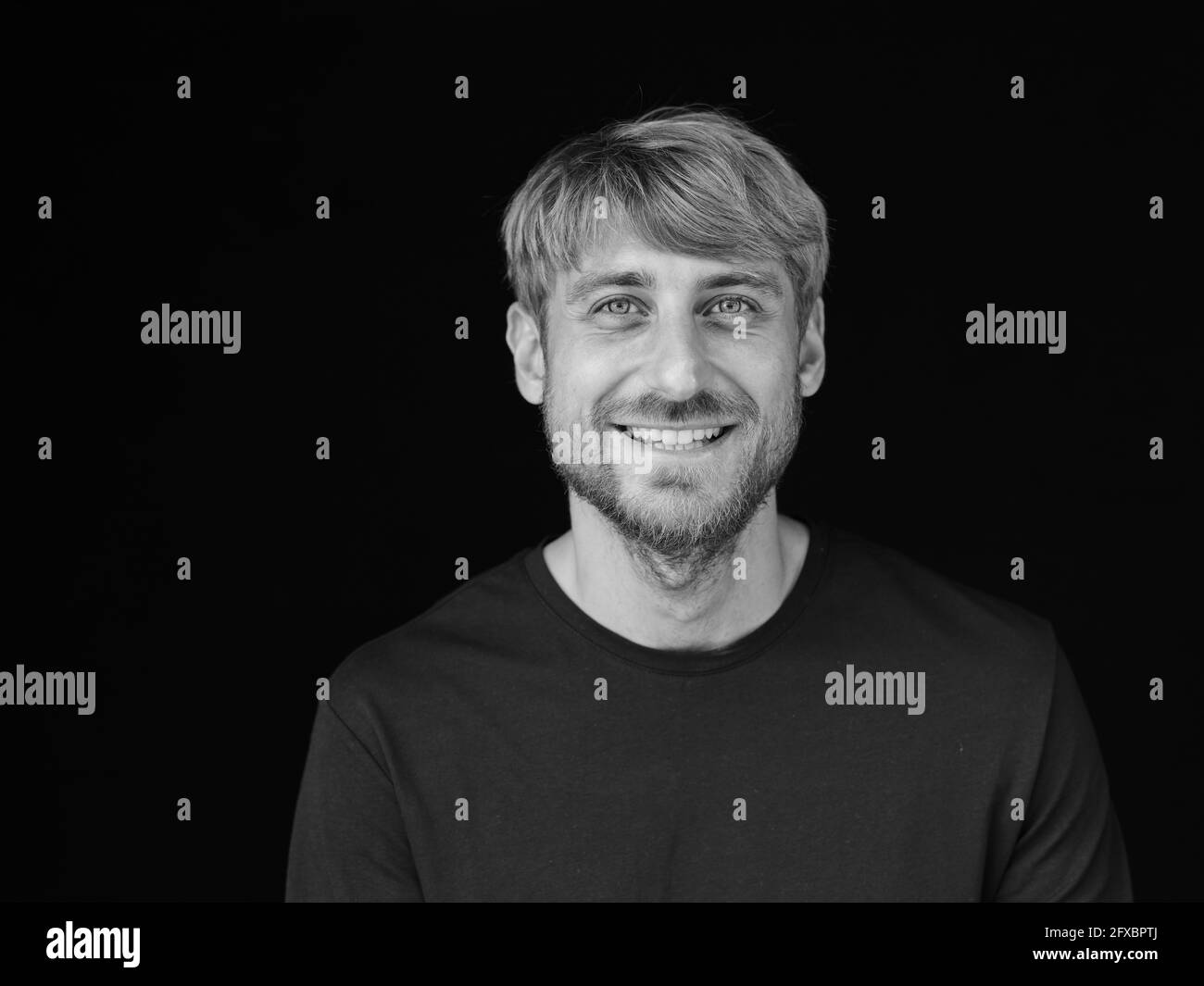 Handsome man smiling against black background Stock Photo - Alamy