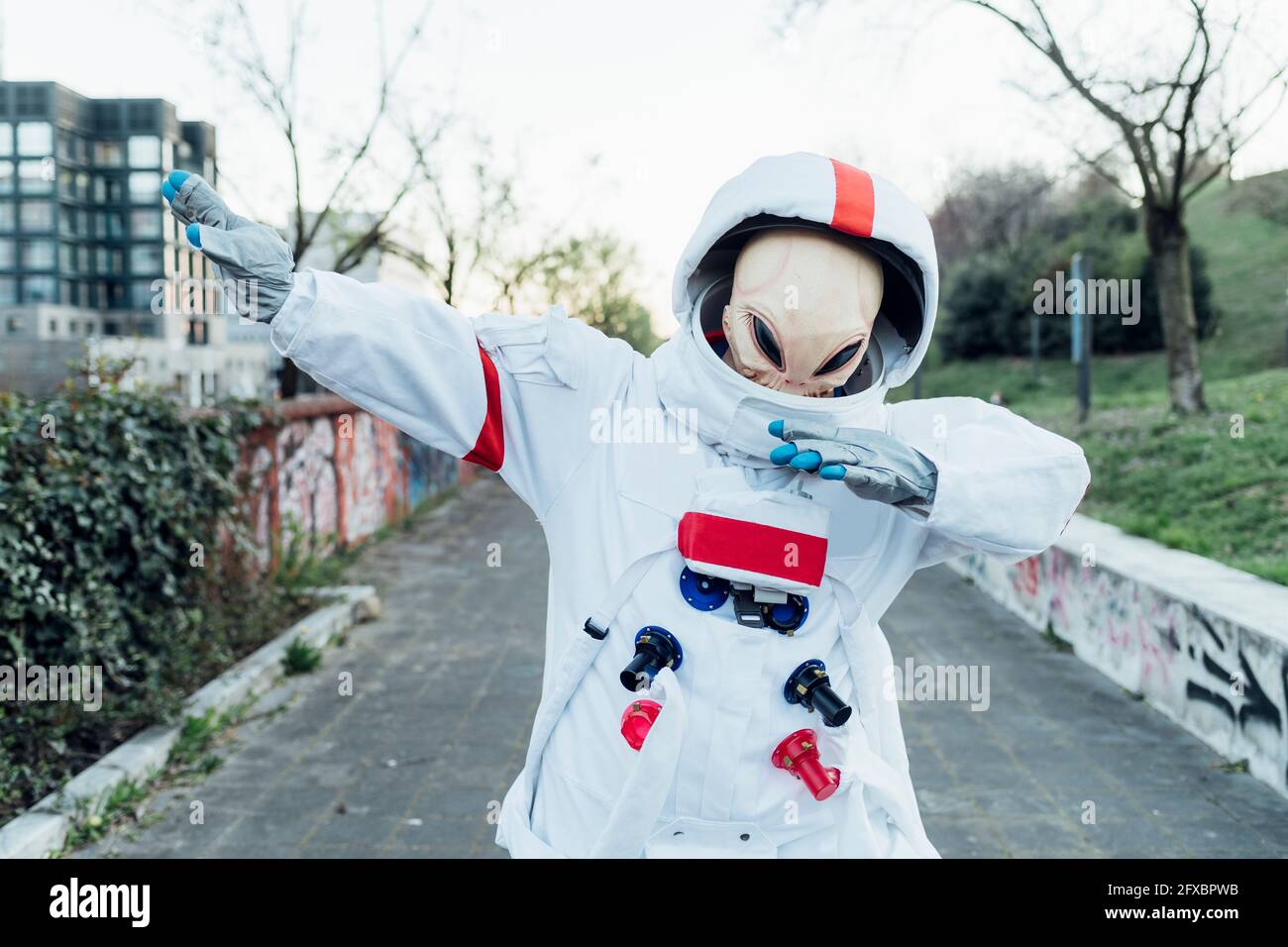Young female astronaut with alien mask doing dab on footpath Stock ...