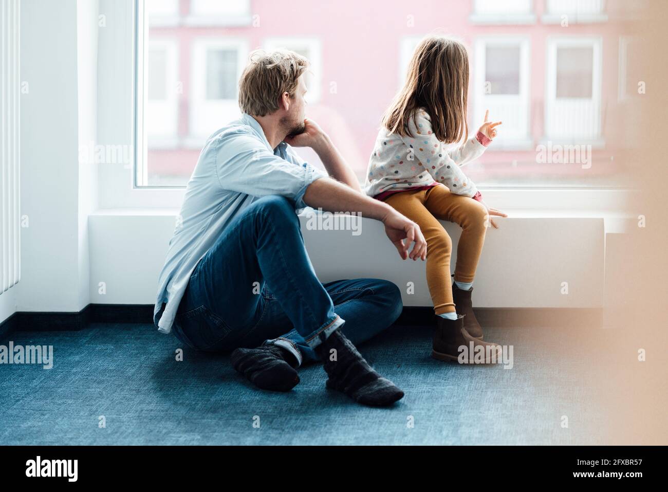 Father and daughter looking through window at home Stock Photo - Alamy