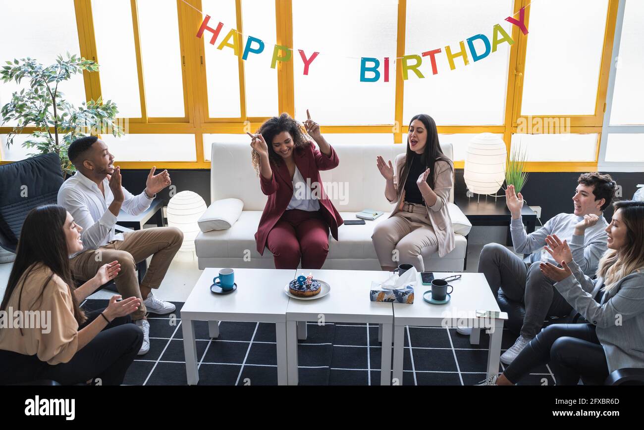 Male and female professionals clapping during birthday celebration at ...