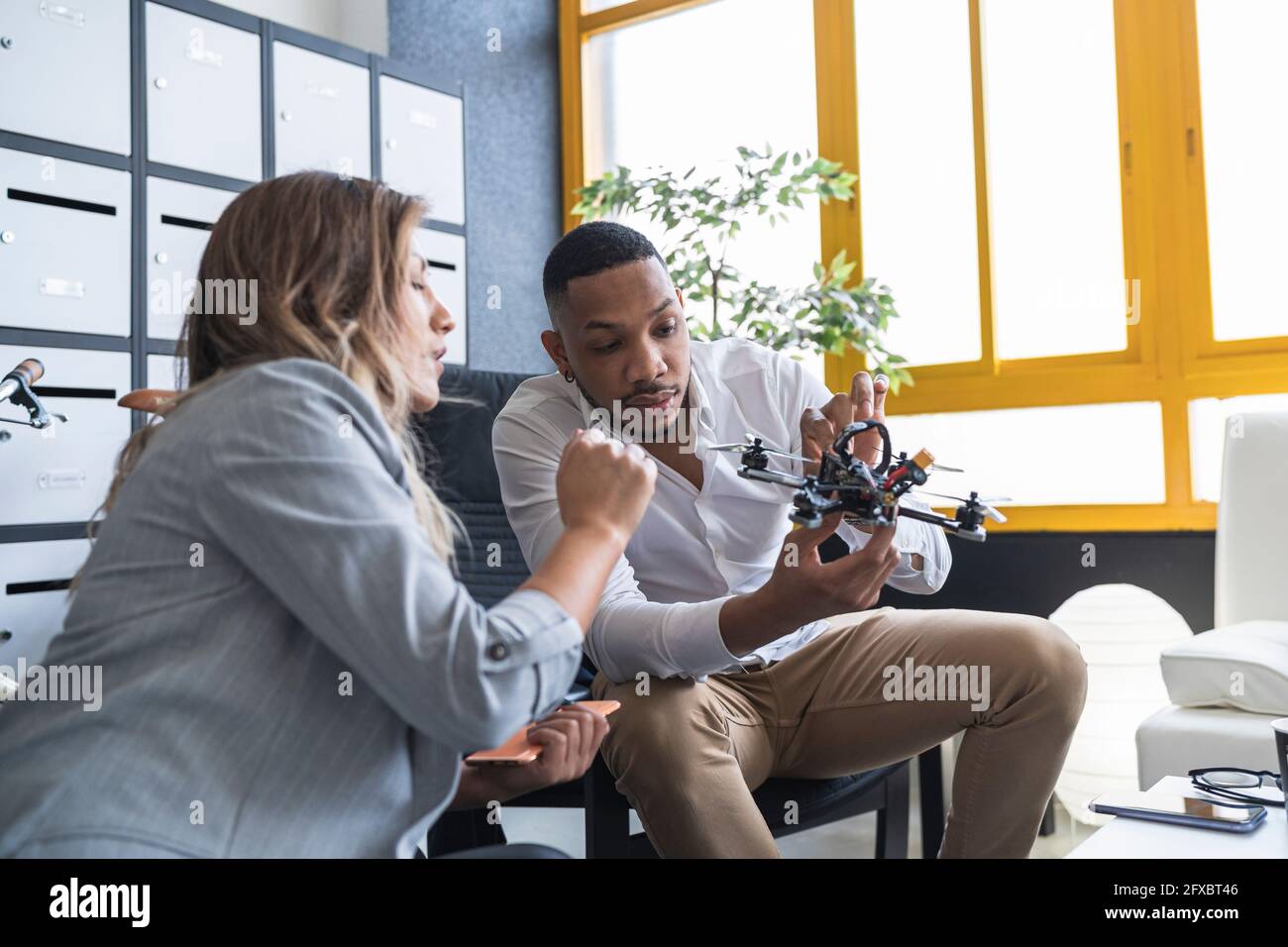 Businessman explaining drone model to female colleague in coworking ...