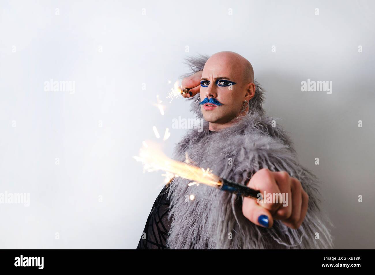 Young man holding firework against white background Stock Photo - Alamy