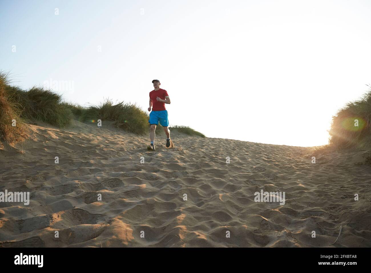 Male athlete running on sand dune at sunrise Stock Photo - Alamy