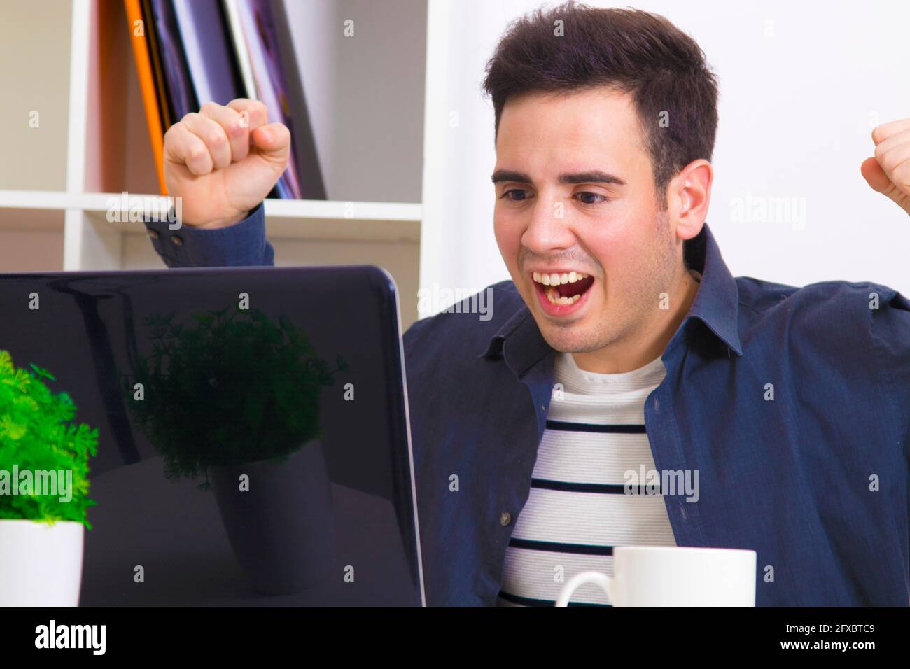 male young celebrating with enthusiasm ahead of the computer laptop ...