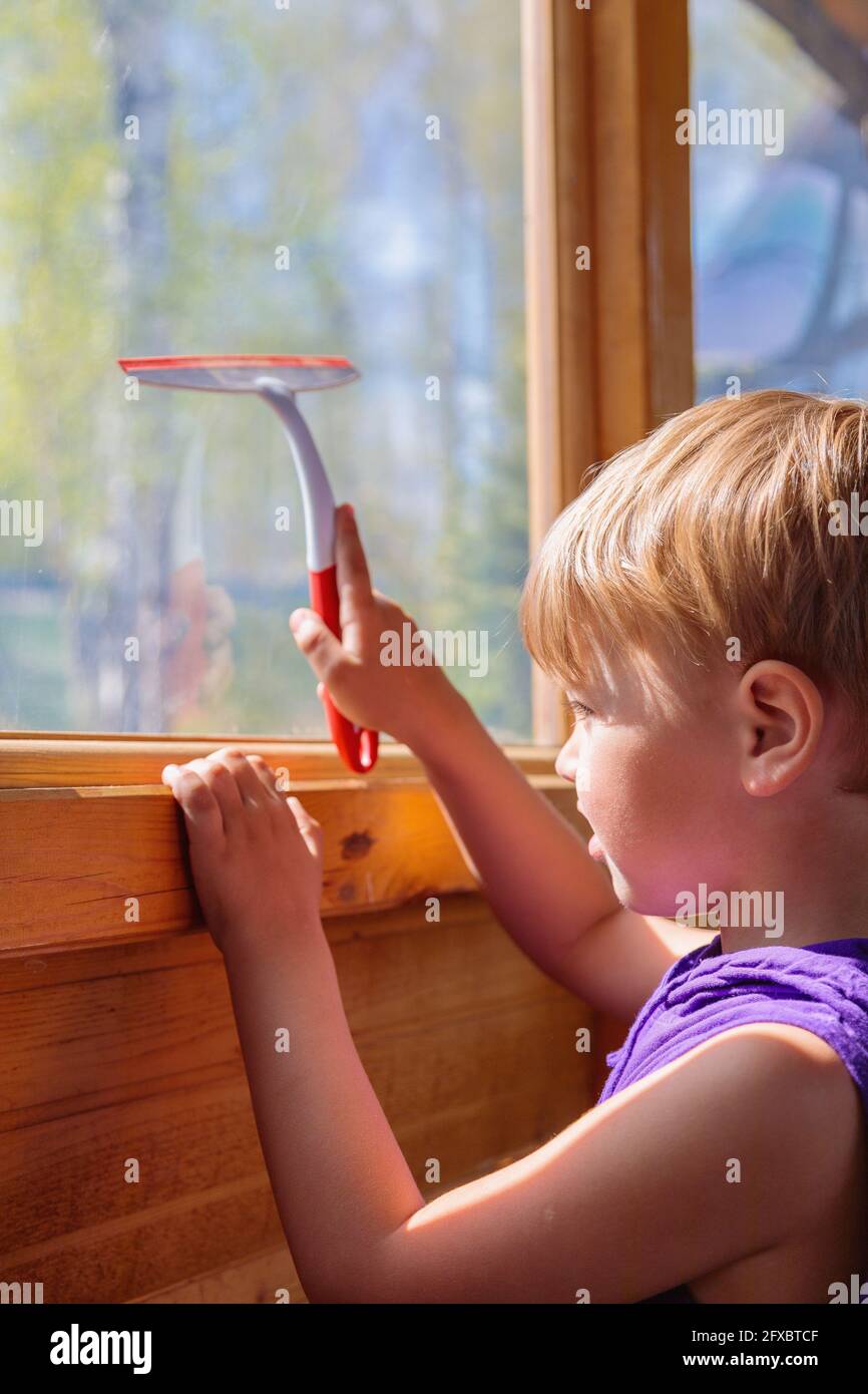 The child washes the windows with a special brush. A child with blond ...