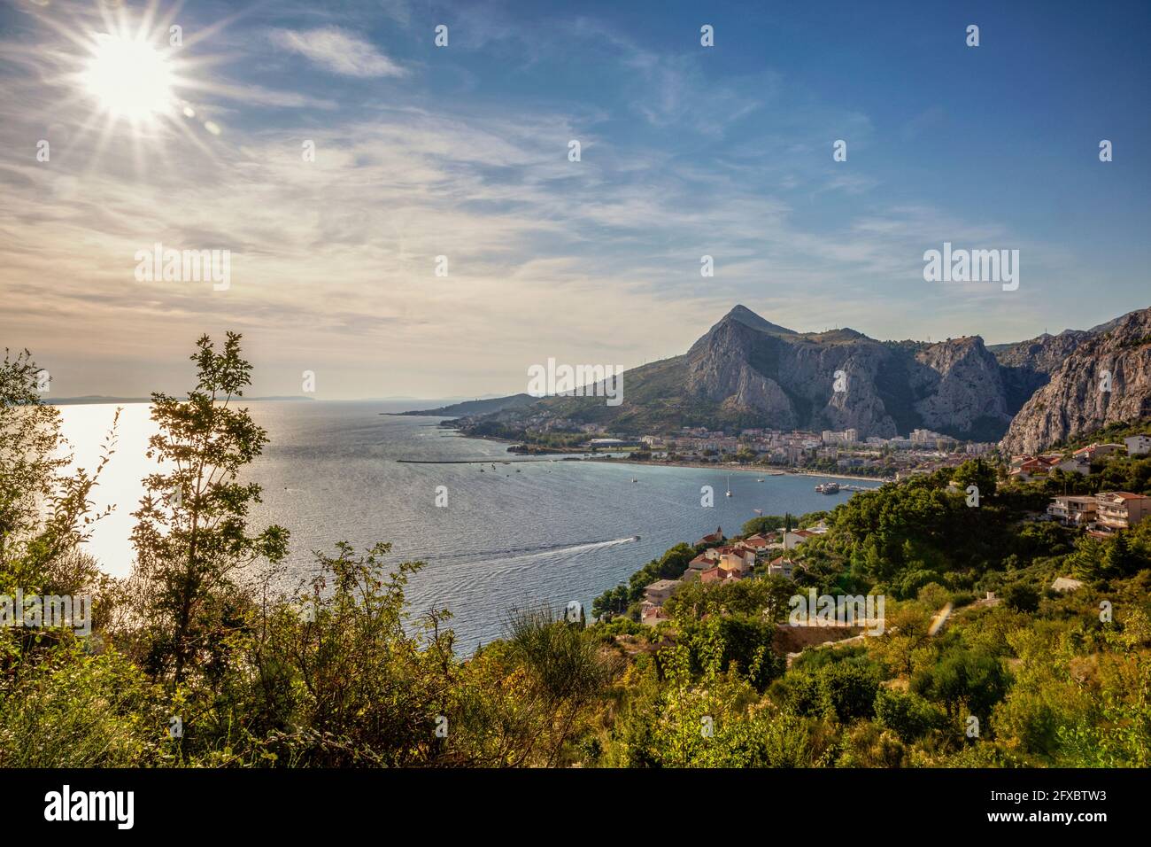 Croatia, Split-Dalmatia County, Omis, Sun setting over coastal town situated at confluence of ...