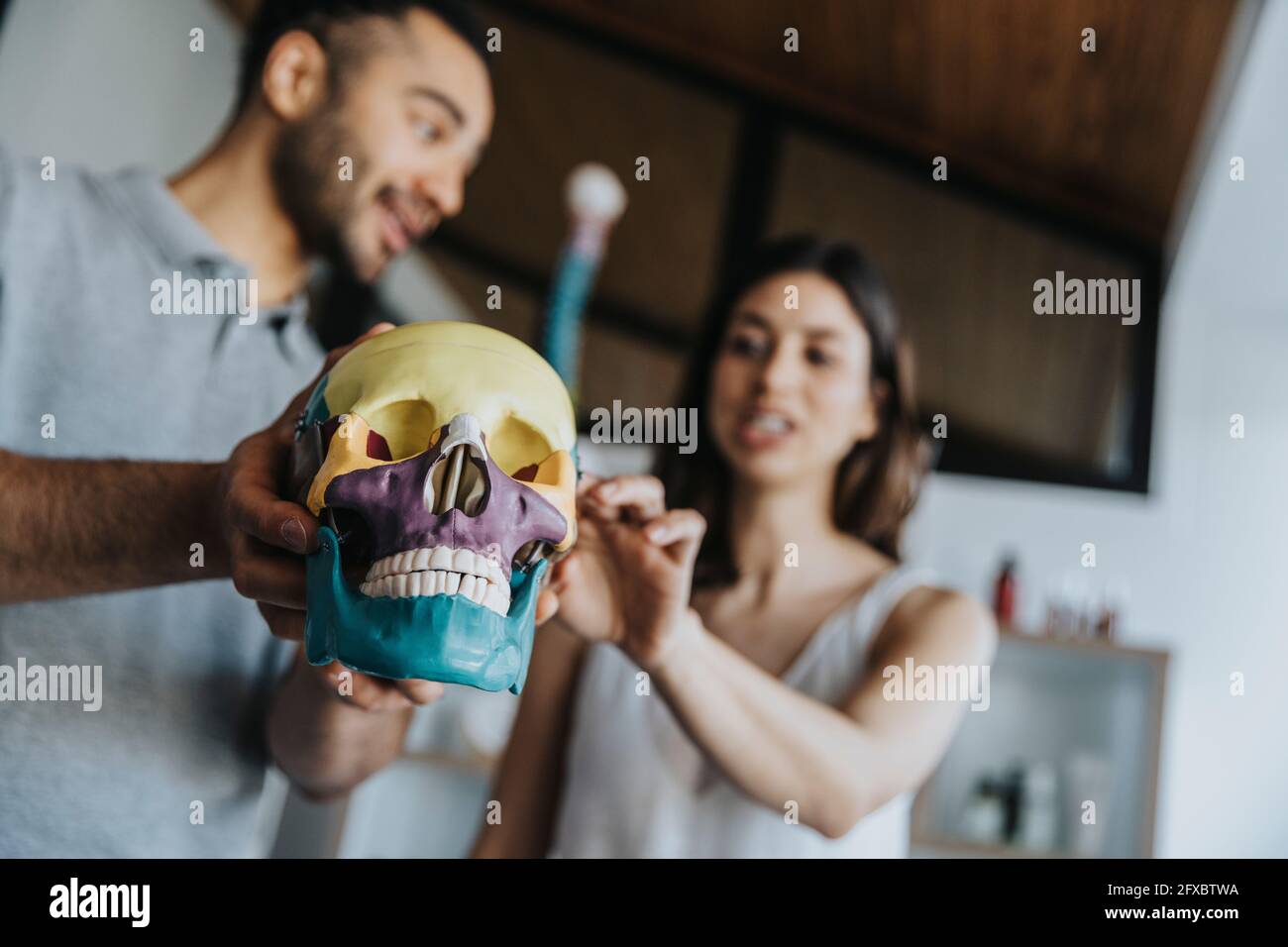 Female patient touching skull model while discussing with male physical ...