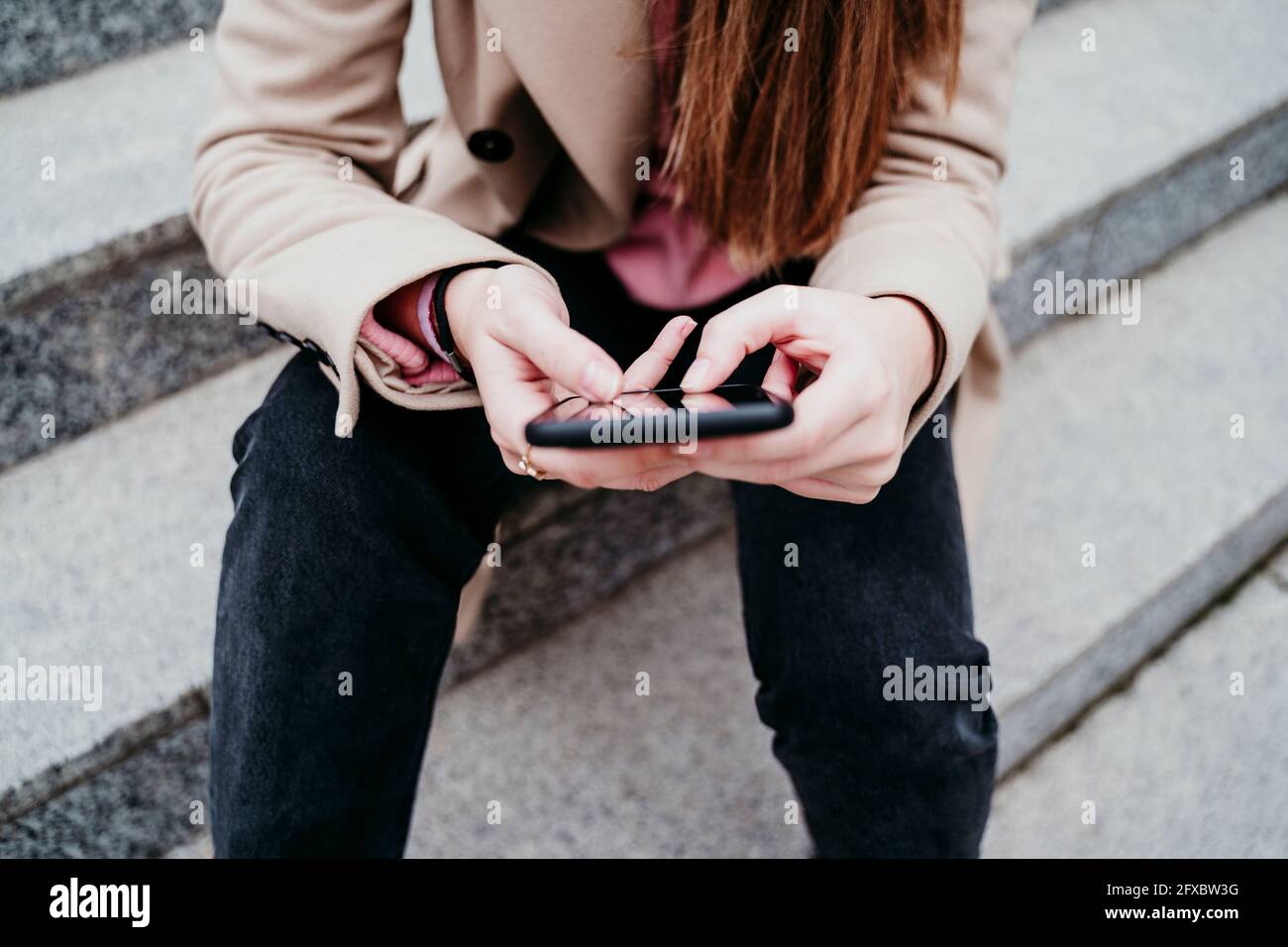 Young woman using smart phone while sitting on steps Stock Photo - Alamy