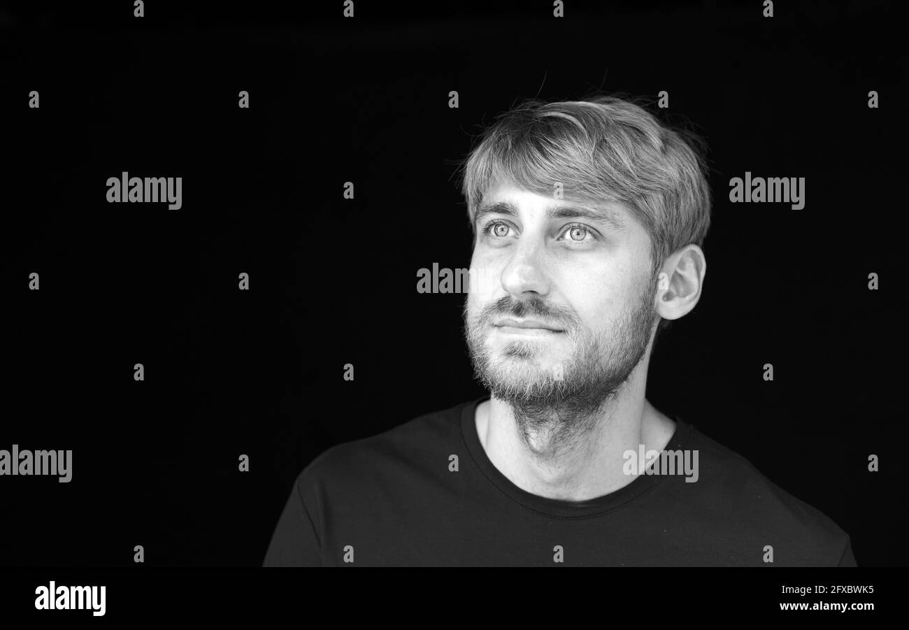 Mid adult man contemplating against black background Stock Photo - Alamy