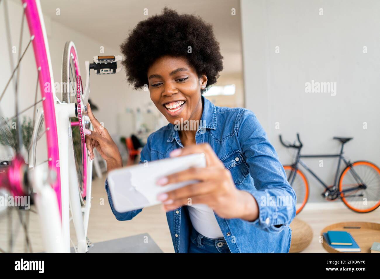 Female influencer smiling while vlogging through mobile phone at home ...