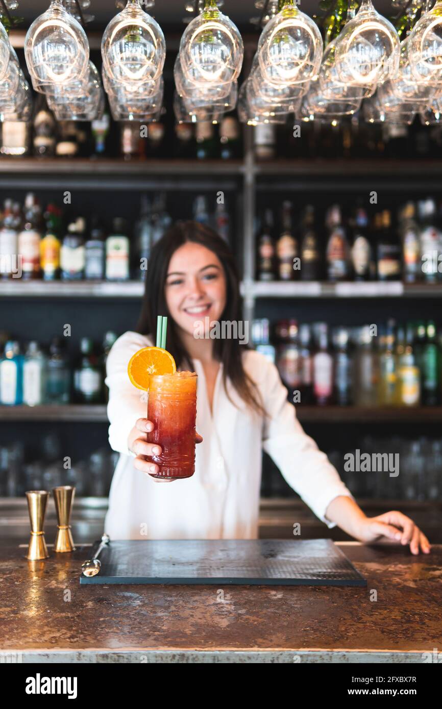 Smiling female bartender giving glass of cocktail at counter Stock ...