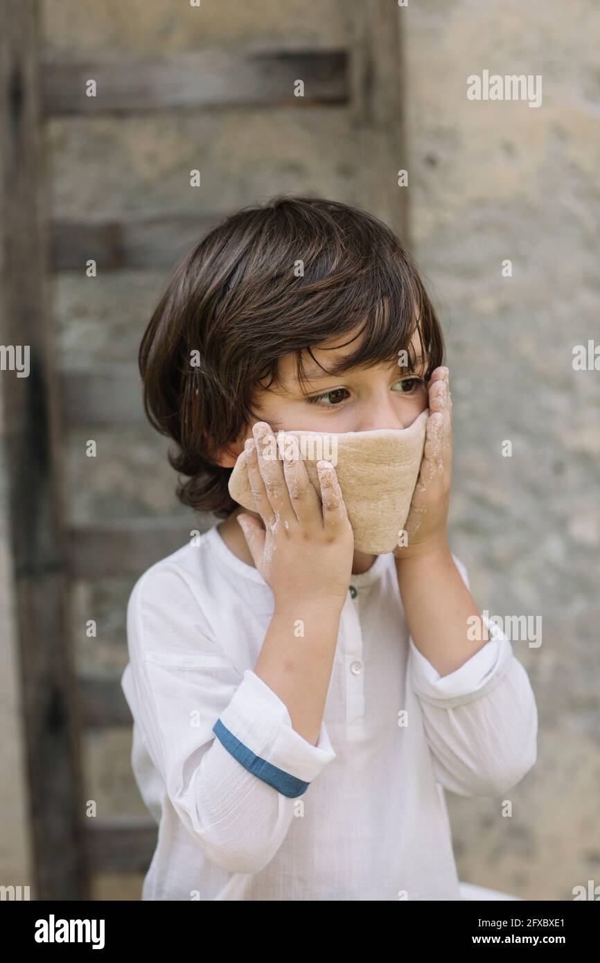 Cute boy covering face with dough at back yard Stock Photo - Alamy