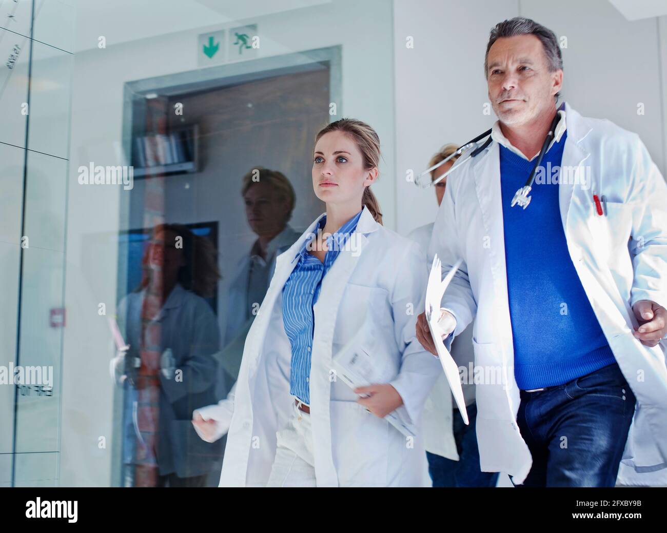 Female and male doctors running in corridor during urgency in hospital ...