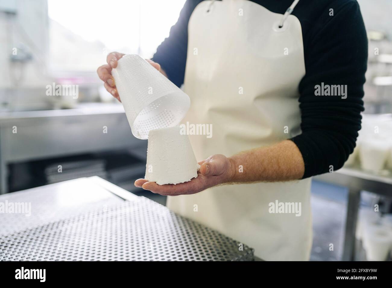 Mature male chef removing cheese from container in factory Stock Photo ...