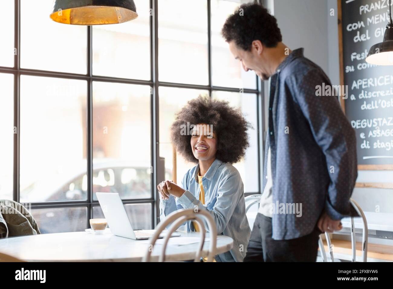 Smiling female professional discussing with male coworker in cafe Stock ...