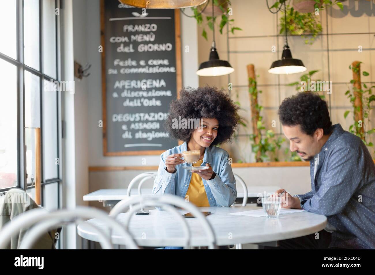 Female professional having coffee while sitting with male customer at ...