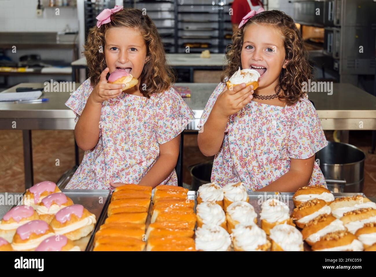 Twin sisters eating pastry in bakery Stock Photo - Alamy